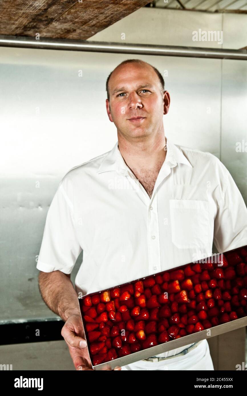 Smiling confectioner holds a strawberry cake Stock Photo - Alamy