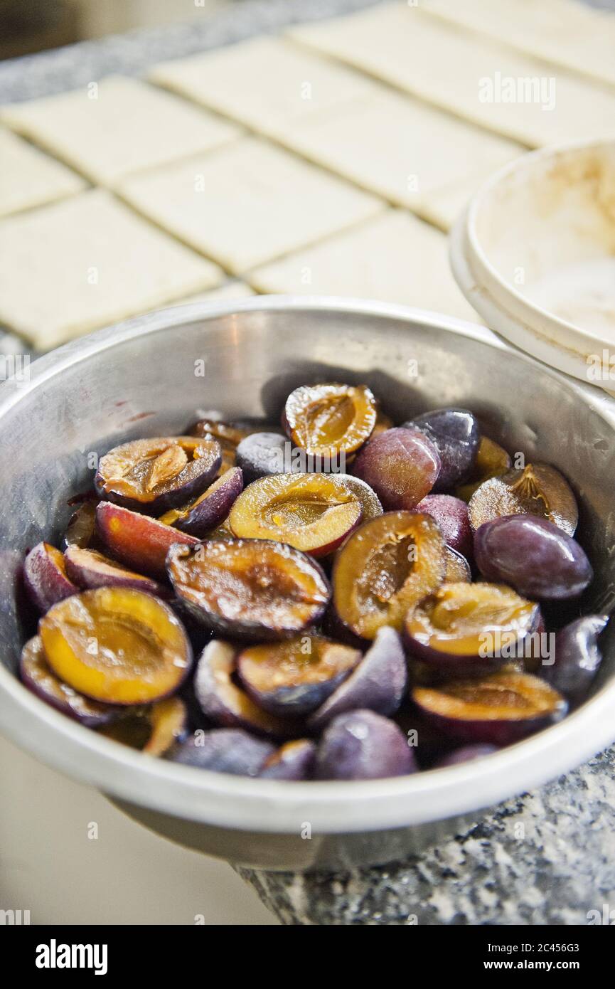 Halved plums in a bowl and puff pastry Stock Photo - Alamy