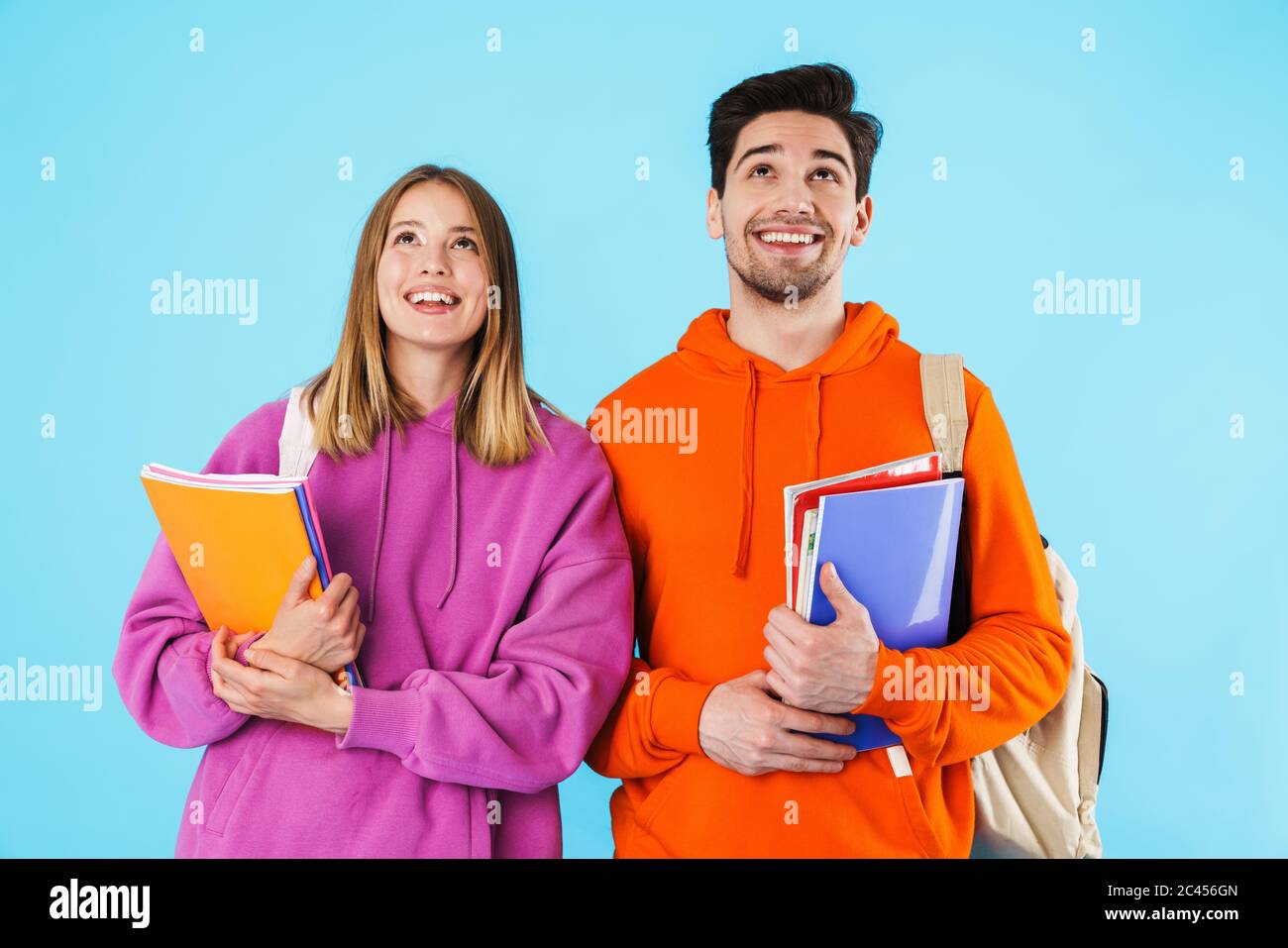 Portrait of a cheerful young couple of students wearing backpacks ...
