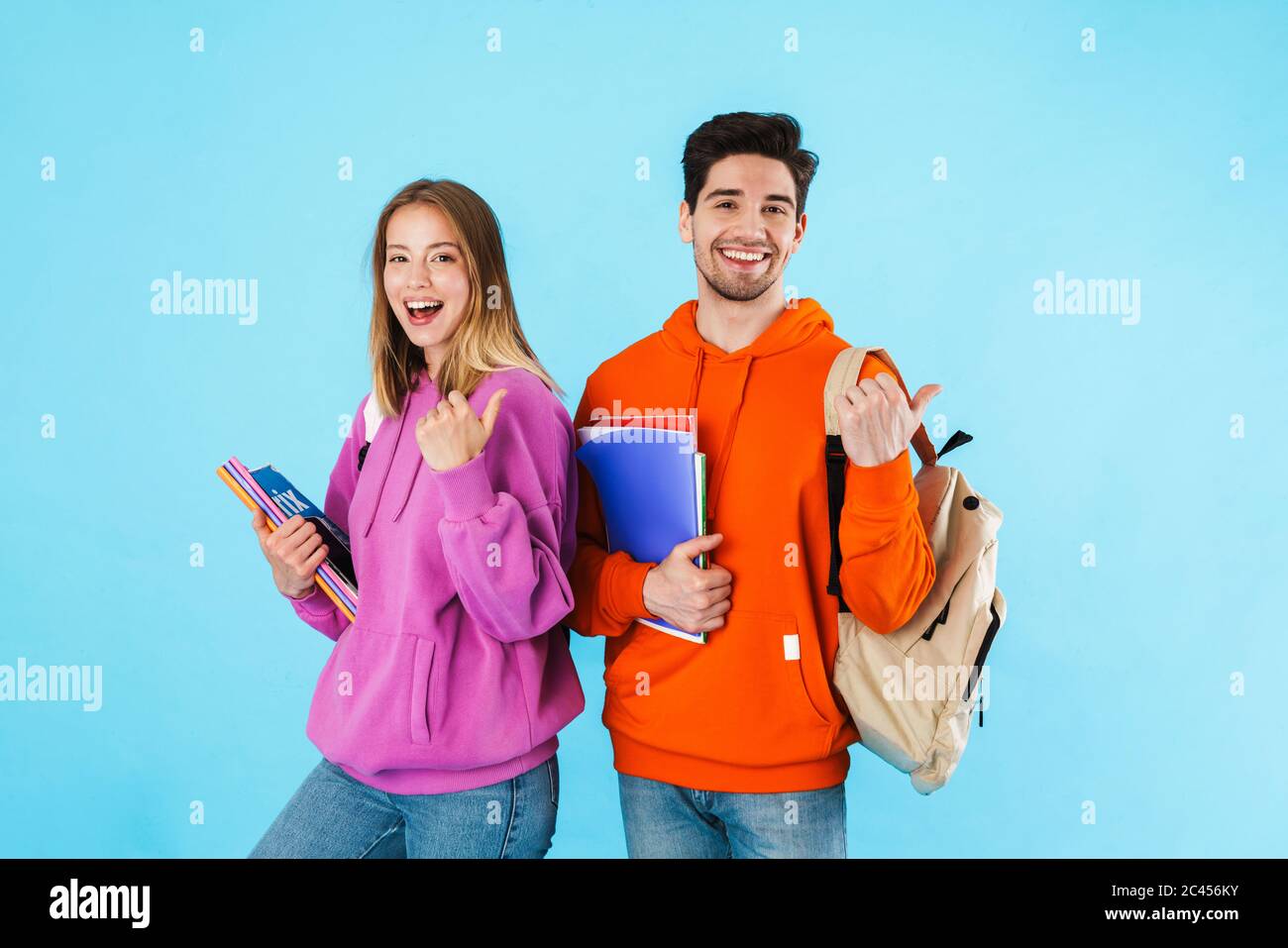 Portrait of a cheerful young couple of students wearing backpacks ...