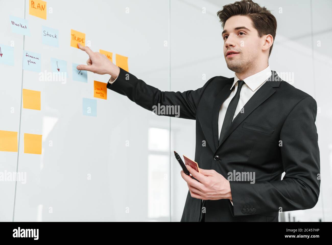 Image of concentrated young businessman wearing suit using stickers ...