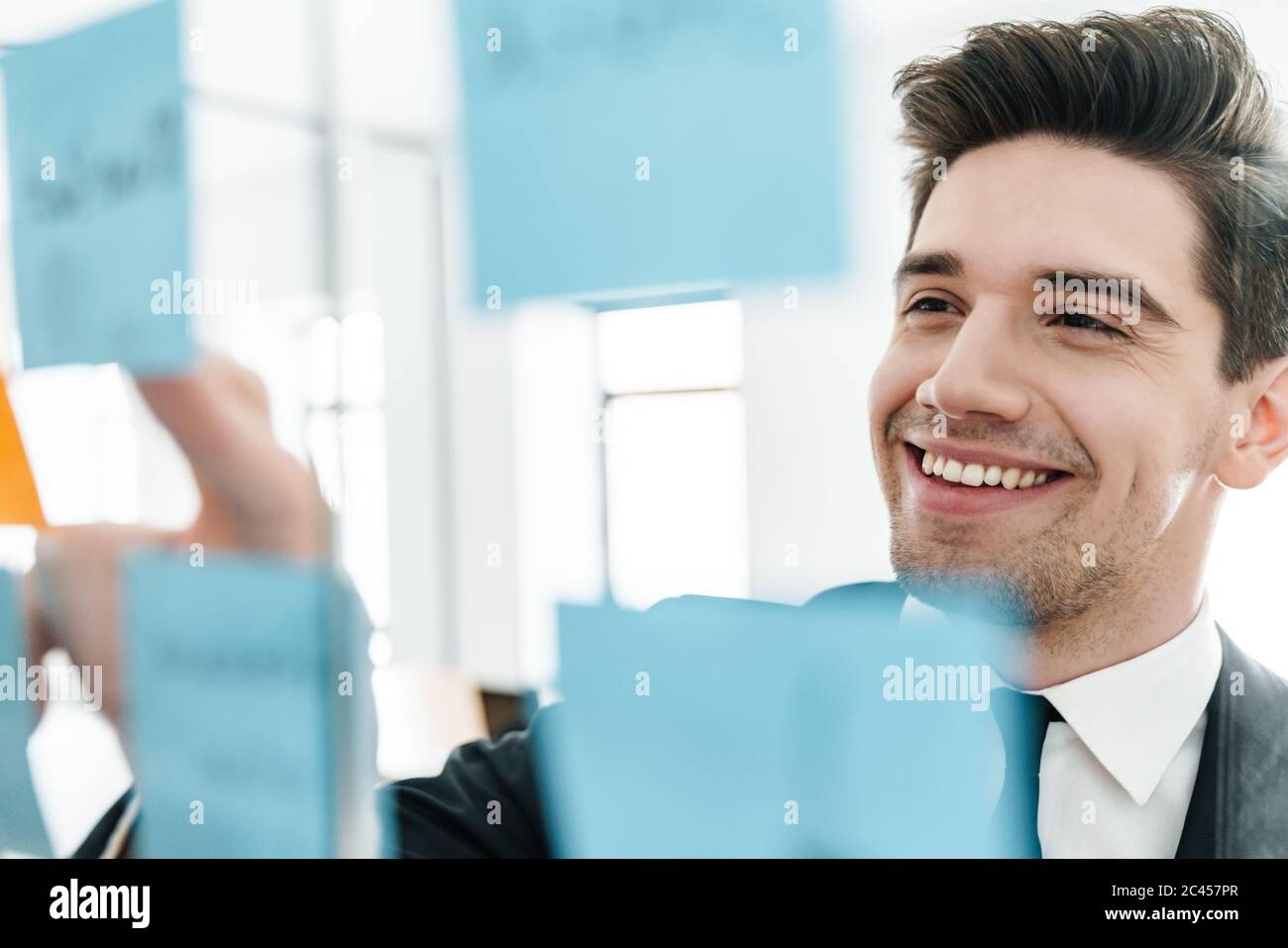 Image of cheerful caucasian young businessman wearing suit using ...