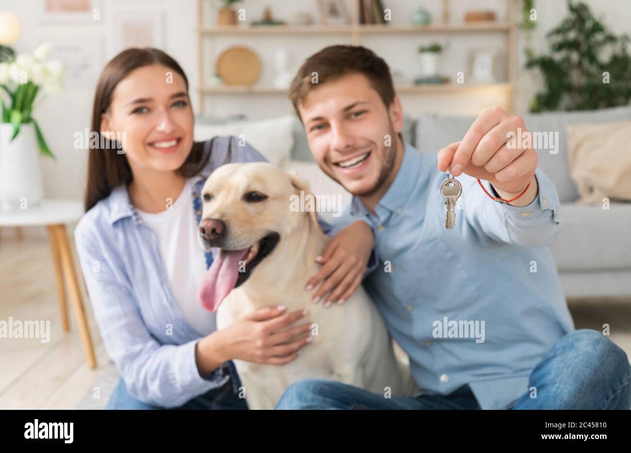 Young happy couple with dog showing keys from new home Stock Photo - Alamy