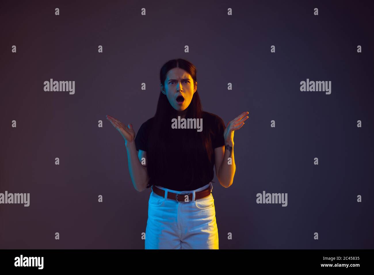 Angry, shocked. Caucasian young woman's portrait on dark studio ...