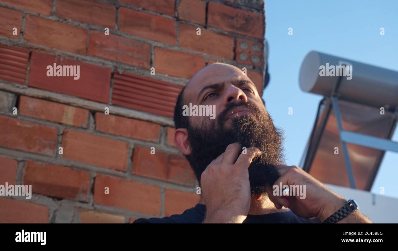 Bearded man with an angry face standing near the brick wall Stock Photo ...