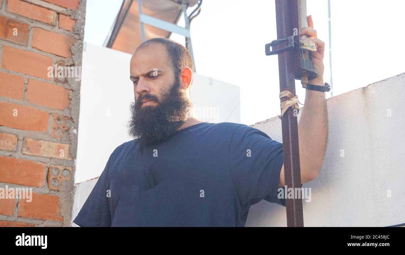 White man with a beard standing on the roof and holding a column Stock ...