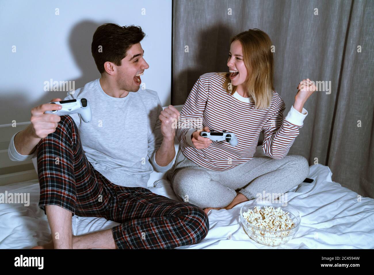Portrait of delighted cute couple holding joysticks and making winner ...