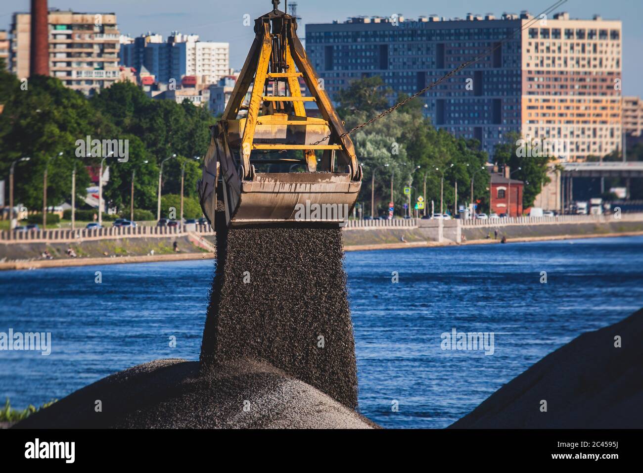 Bulk-handling crane unloading sand, road metal and gravel from cargo ...