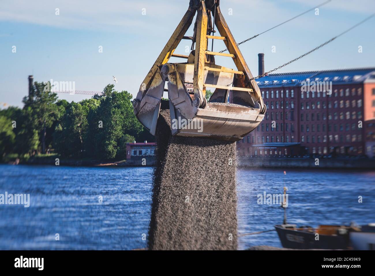 Bulk-handling crane unloading sand, road metal and gravel from cargo ...