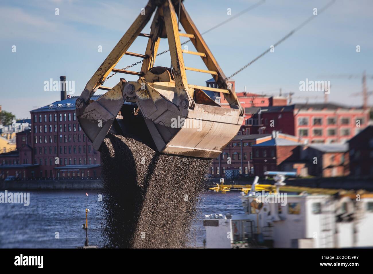 Bulk-handling crane unloading sand, road metal and gravel from cargo ...