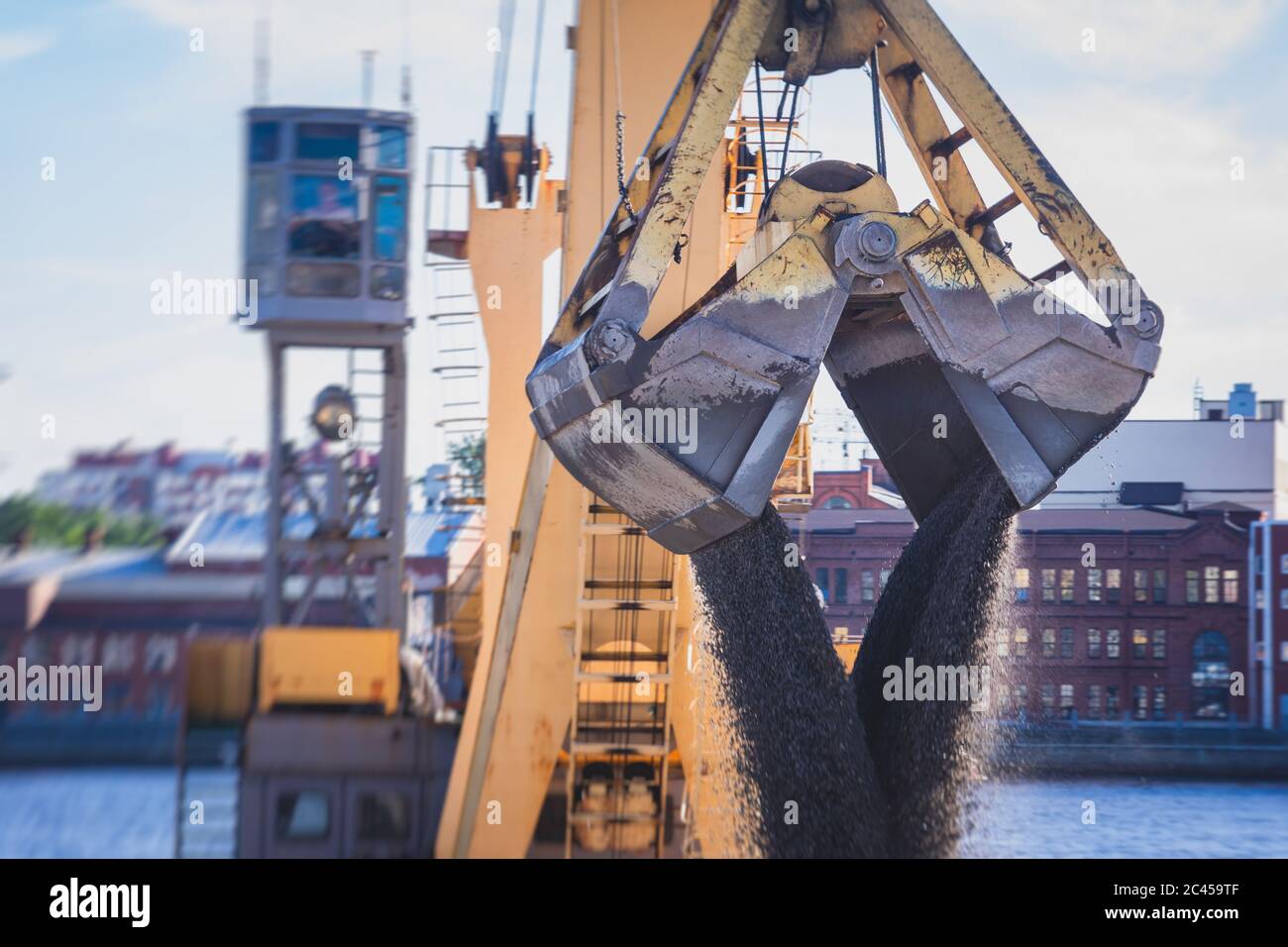 Bulk-handling crane unloading sand, road metal and gravel from cargo ...