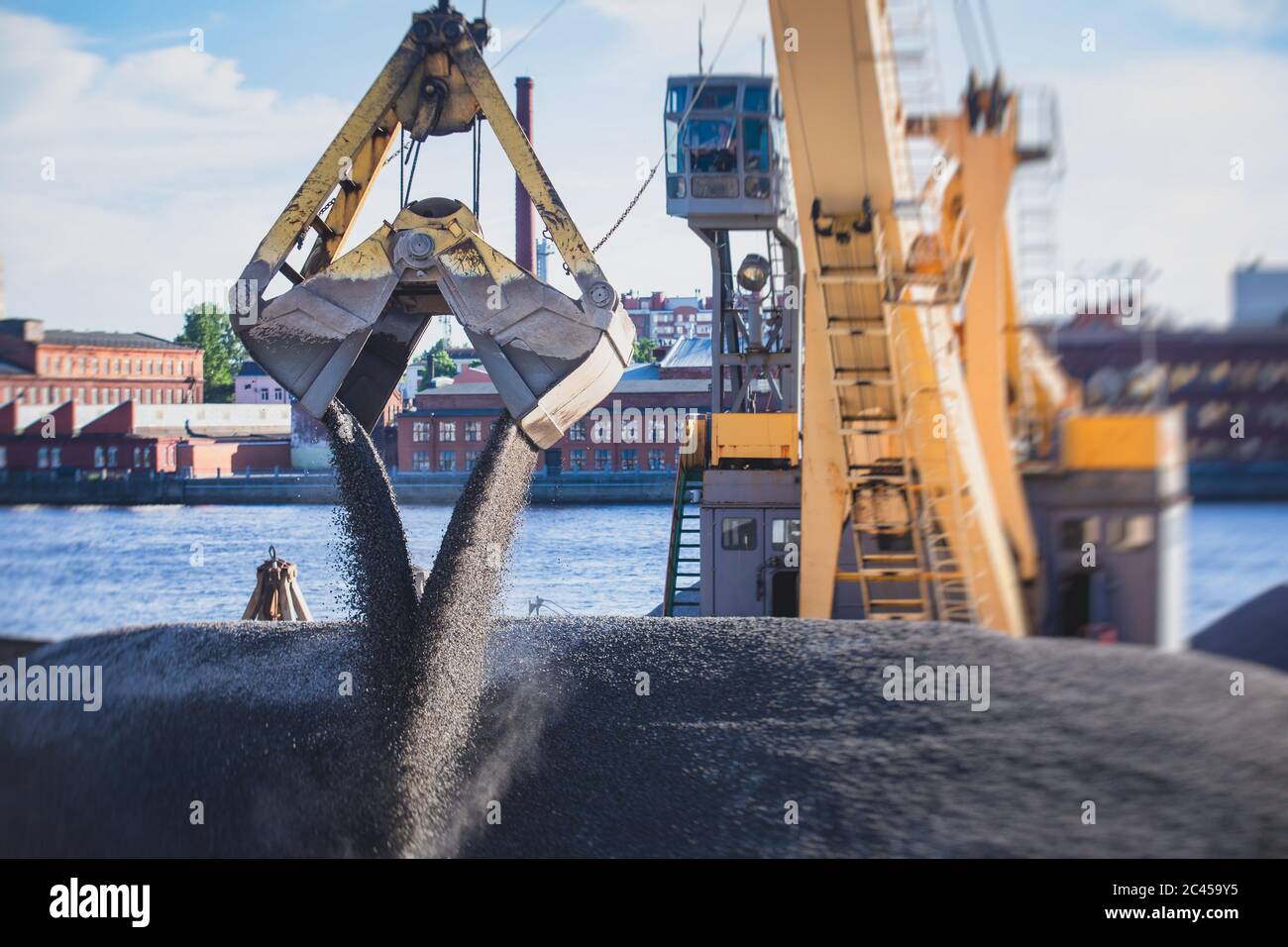 Bulk-handling crane unloading sand, road metal and gravel from cargo ...