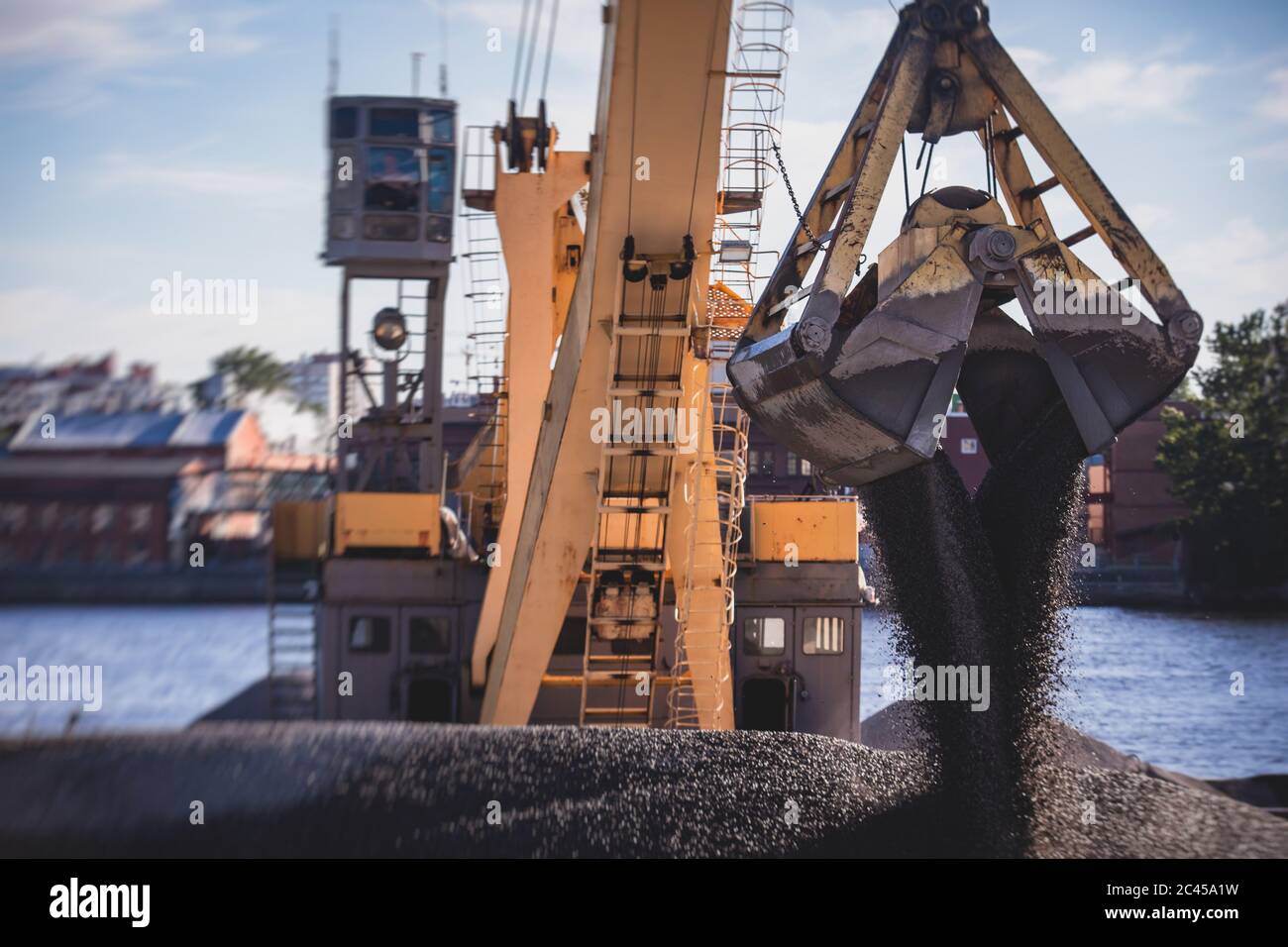 Bulk-handling crane unloading sand, road metal and gravel from cargo ...