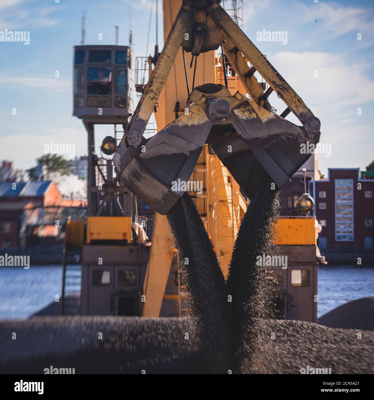 Bulk-handling crane unloading sand, road metal and gravel from cargo ...