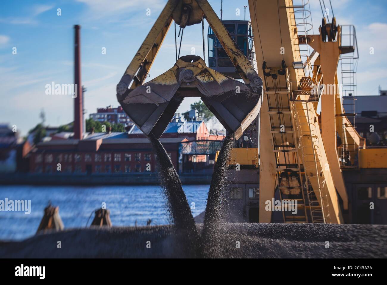 Bulk-handling crane unloading sand, road metal and gravel from cargo ...