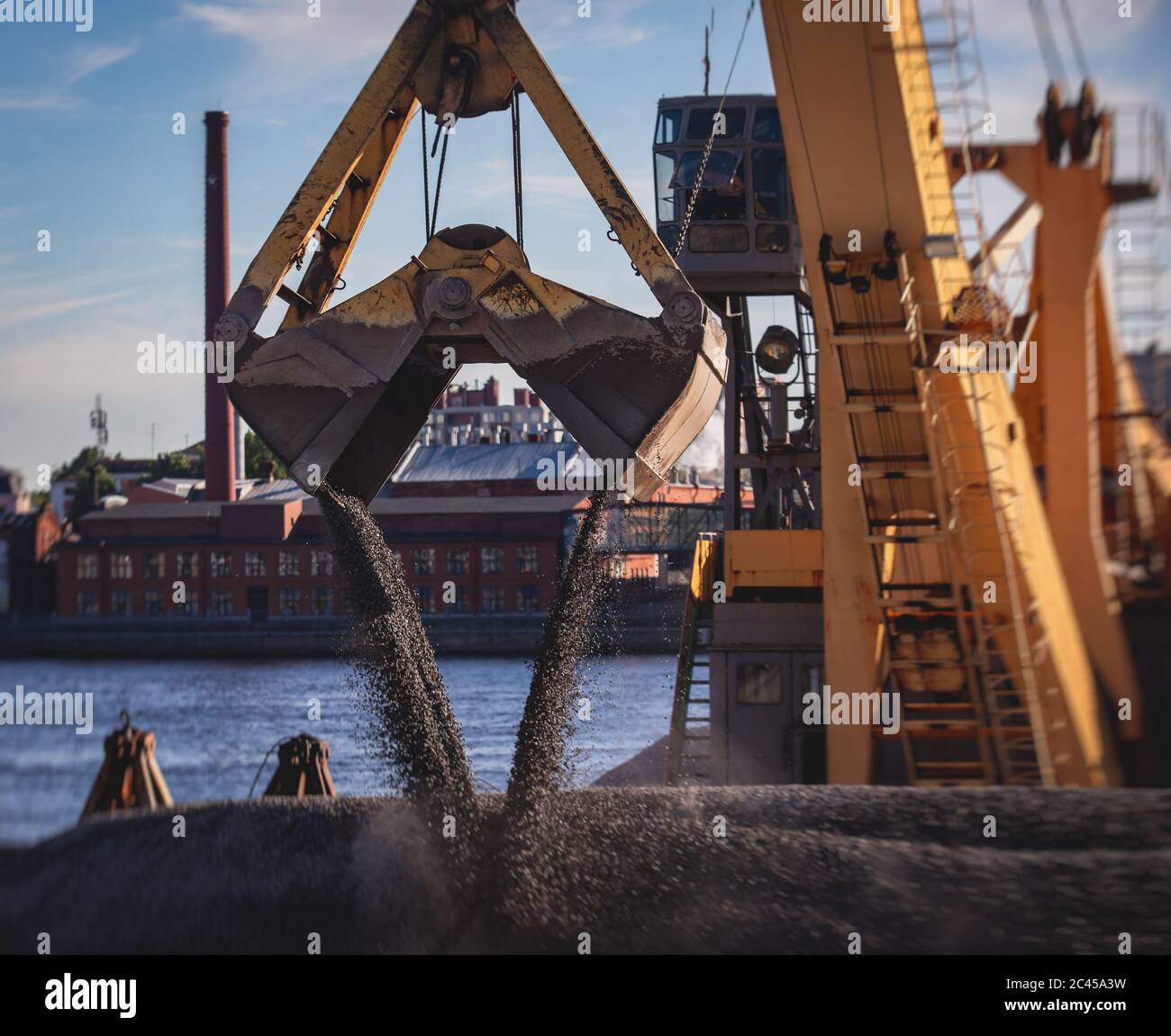 Bulk-handling crane unloading sand, road metal and gravel from cargo ...