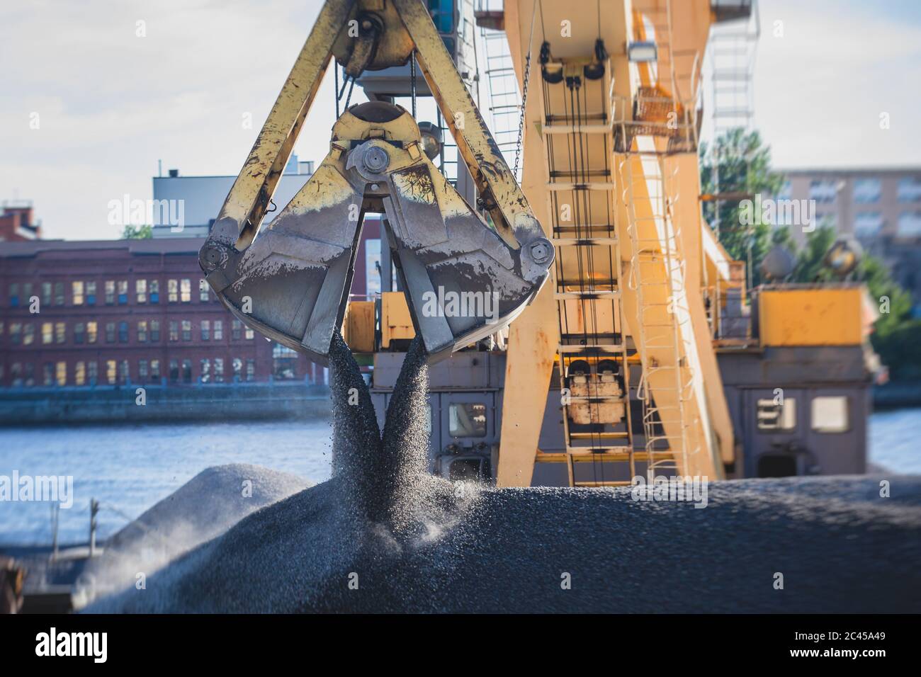 Bulk-handling crane unloading sand, road metal and gravel from cargo ...