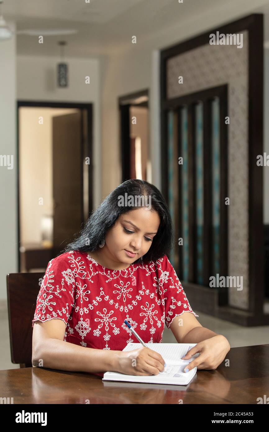 An Indian woman writing notes in her diary, asian woman sitting in her ...