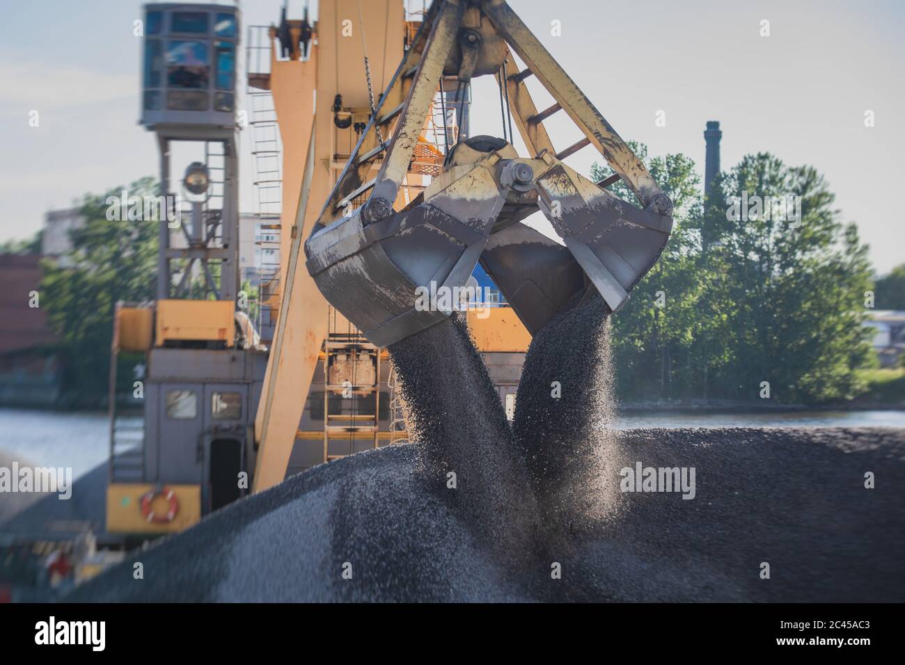 Bulk-handling crane unloading sand, road metal and gravel from cargo ...