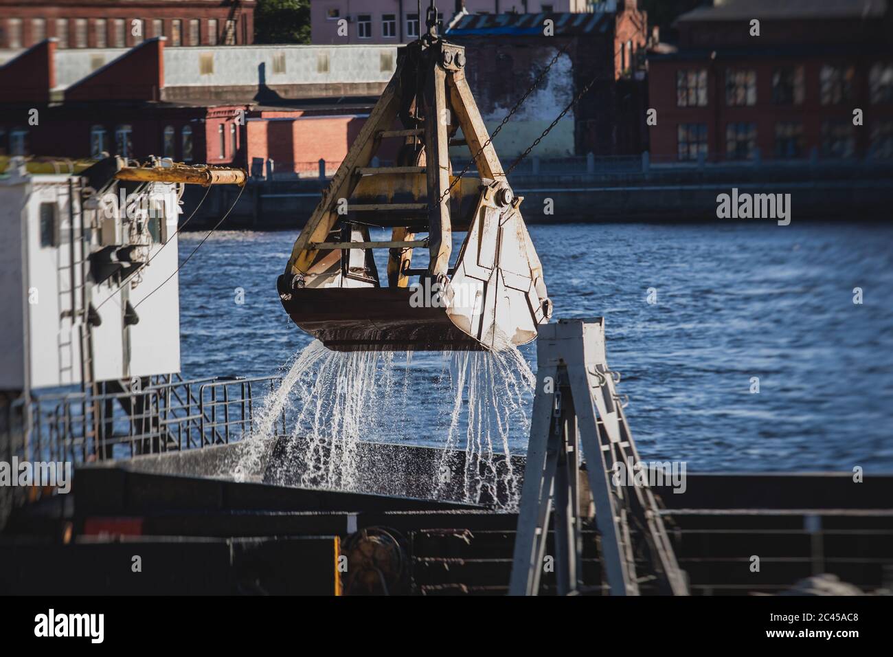 Bulk-handling crane unloading sand, road metal and gravel from cargo ...