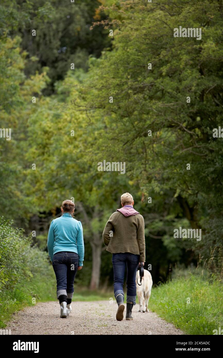 Two women go for a walk with a dog Stock Photo - Alamy