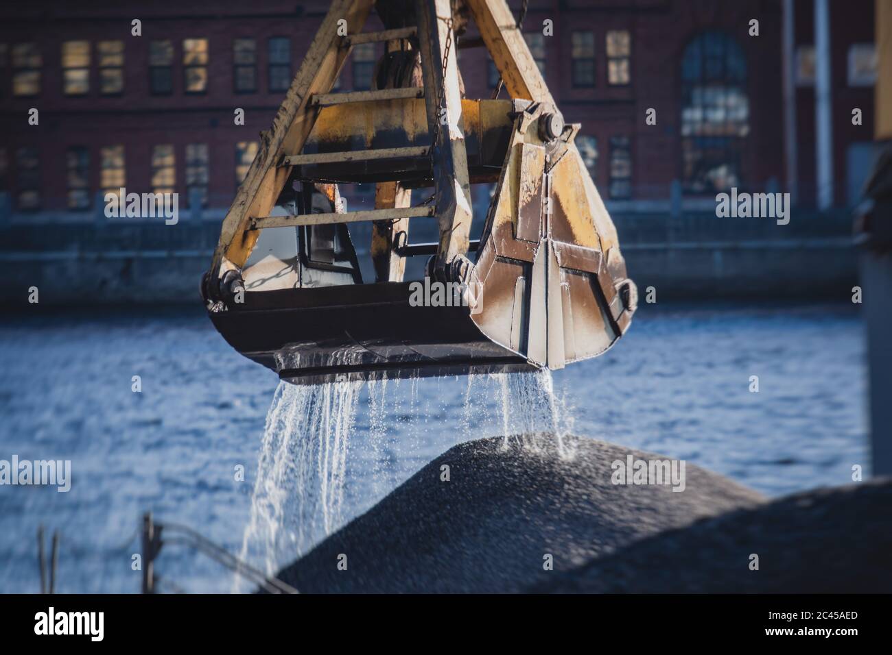 Bulk-handling crane unloading sand, road metal and gravel from cargo ...