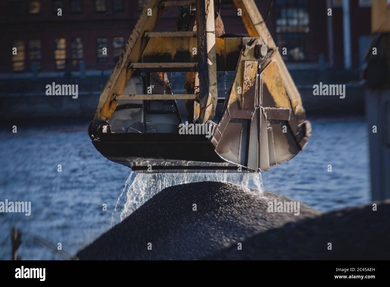 Bulk-handling crane unloading sand, road metal and gravel from cargo ...