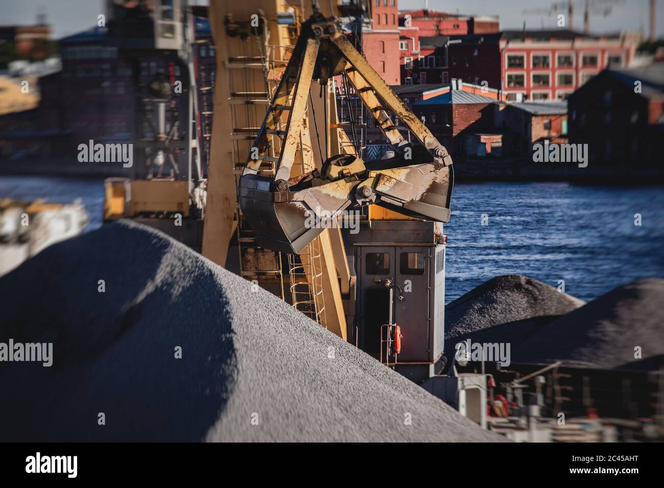 Bulk-handling crane unloading sand, road metal and gravel from cargo ...