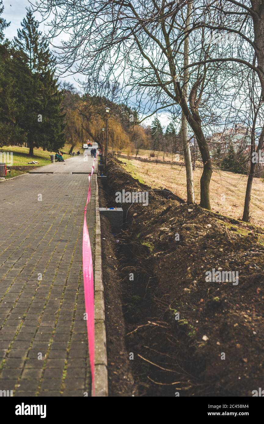 Dug ground separated with red tape in the park Stock Photo - Alamy