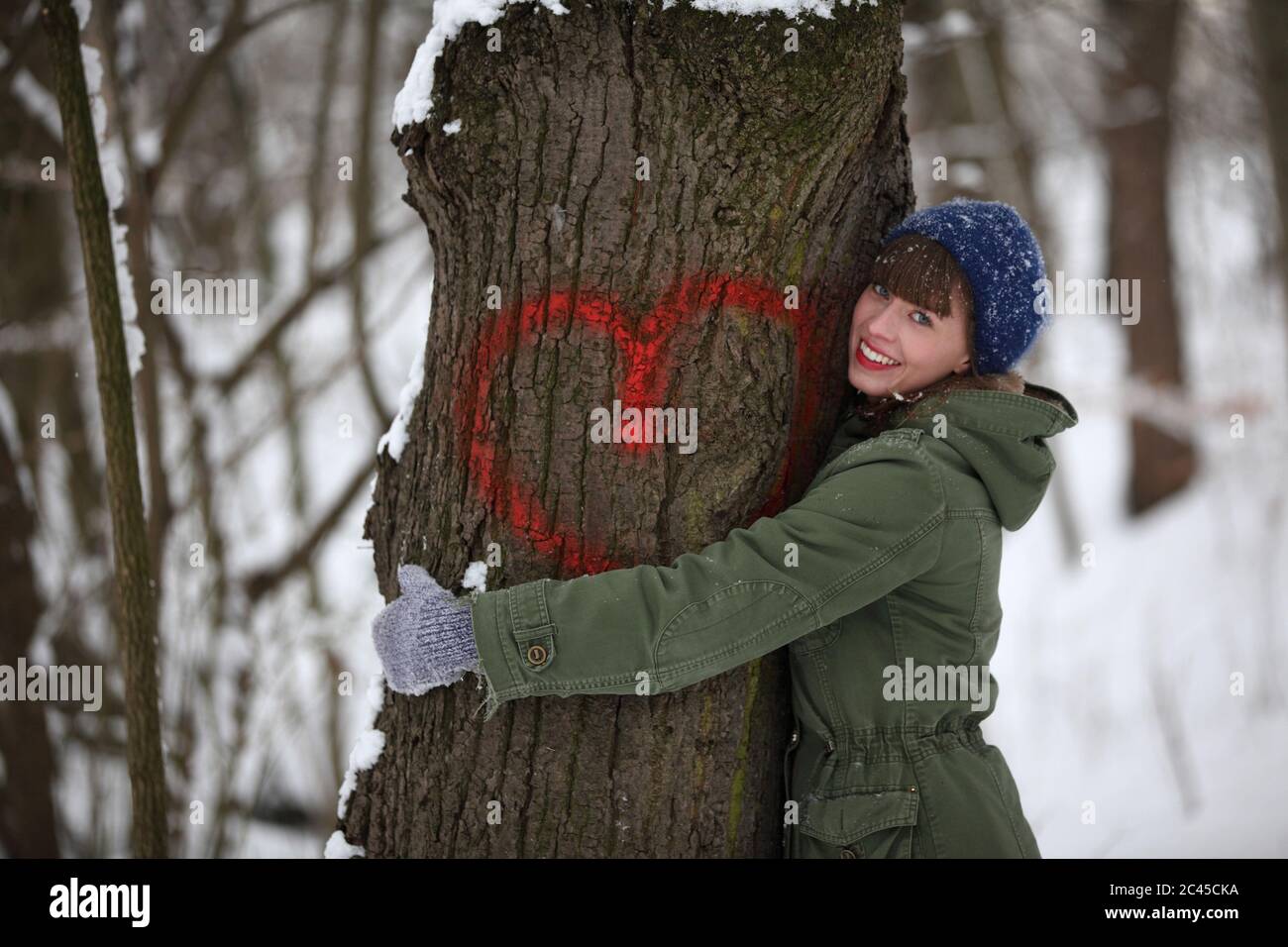 Smiling young woman hugging tree with painted heart Stock Photo - Alamy