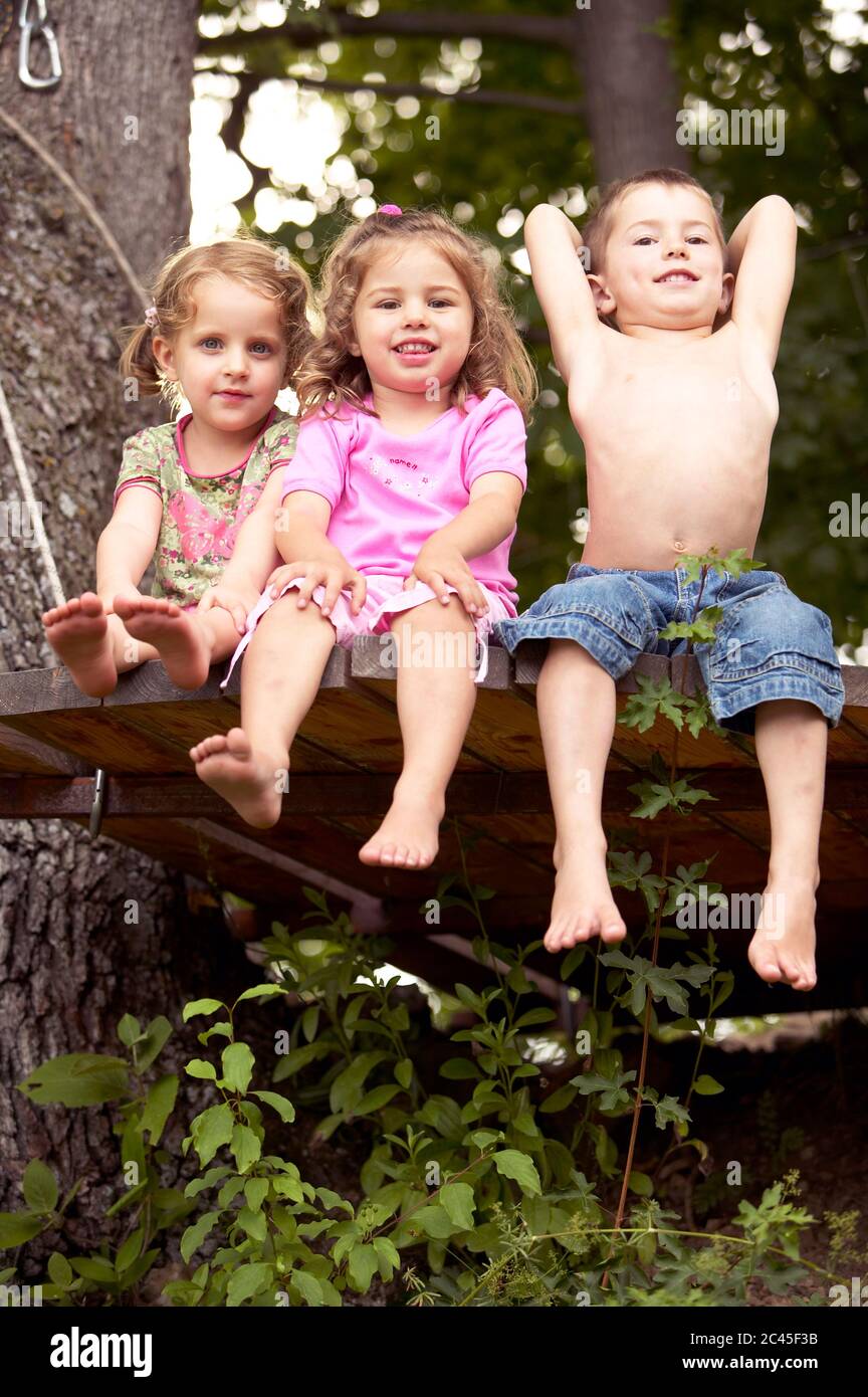 Three children are sitting in the tree house Stock Photo - Alamy