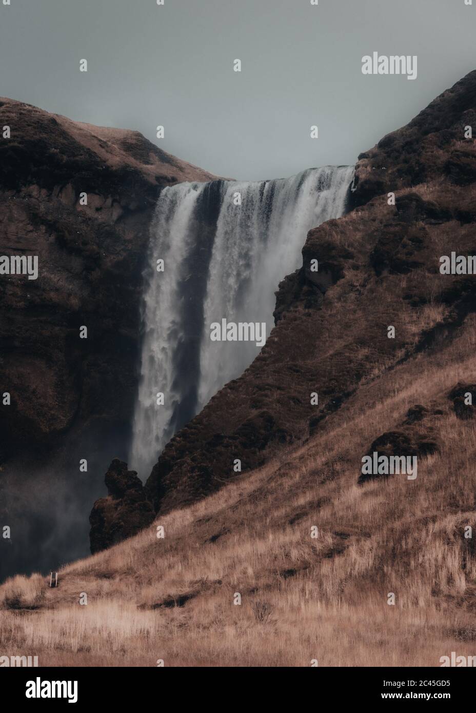 Vertical shot of a small waterfall in the rocks on a gloomy ay in ...