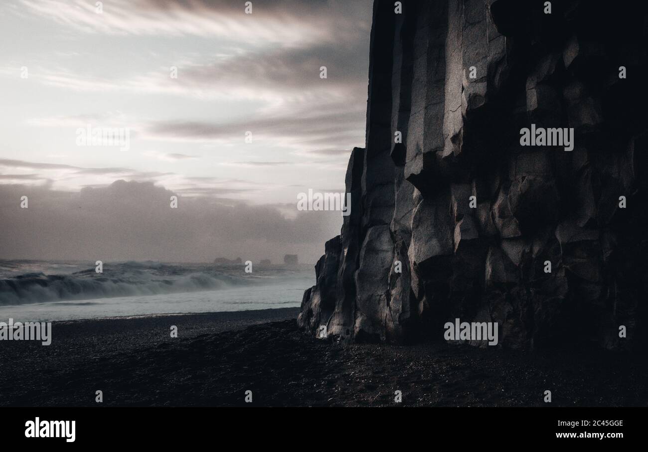 Dark rocks on the body of the ocean on a gloomy day in Iceland Stock ...