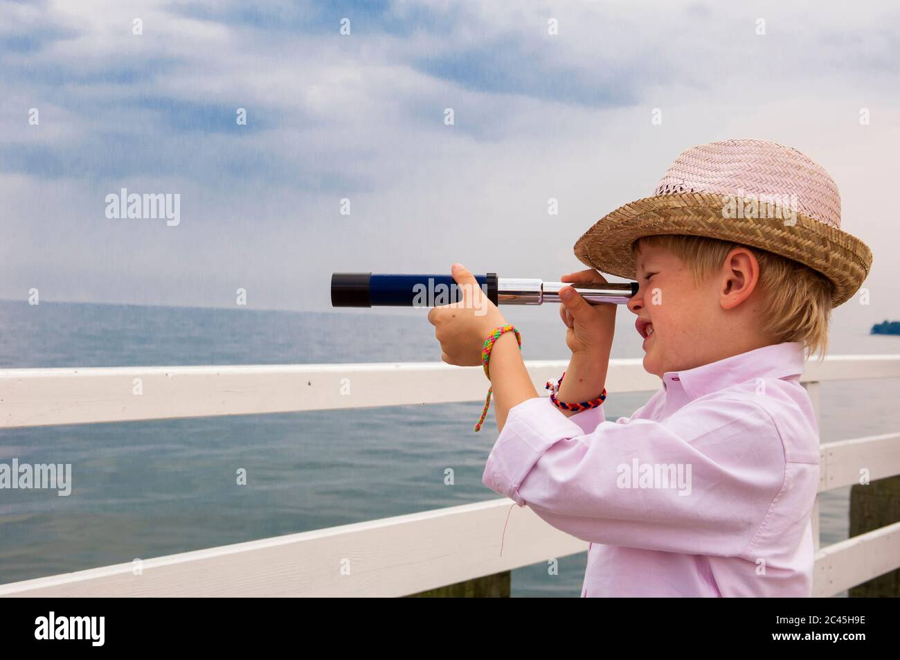 Boy on a jetty looks through a telescope Stock Photo - Alamy