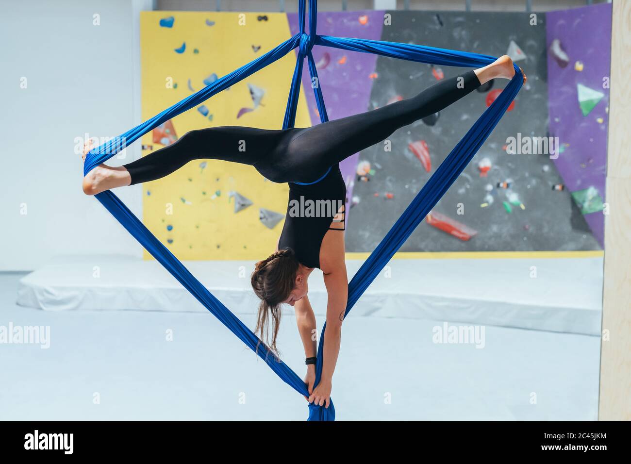 Female acrobat practicing, suspended from blue silk Stock Photo - Alamy