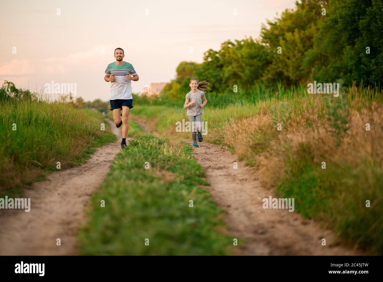 Father and daughter jogging. Cheerful father and daughter run in park ...
