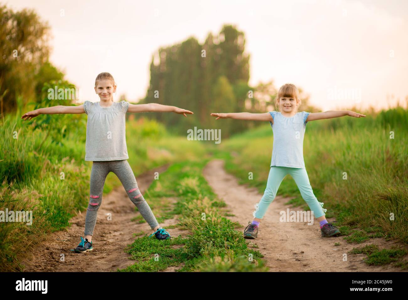 Two little sisters doing exercise outdoors. Healthy lifestyle. Yoga ...