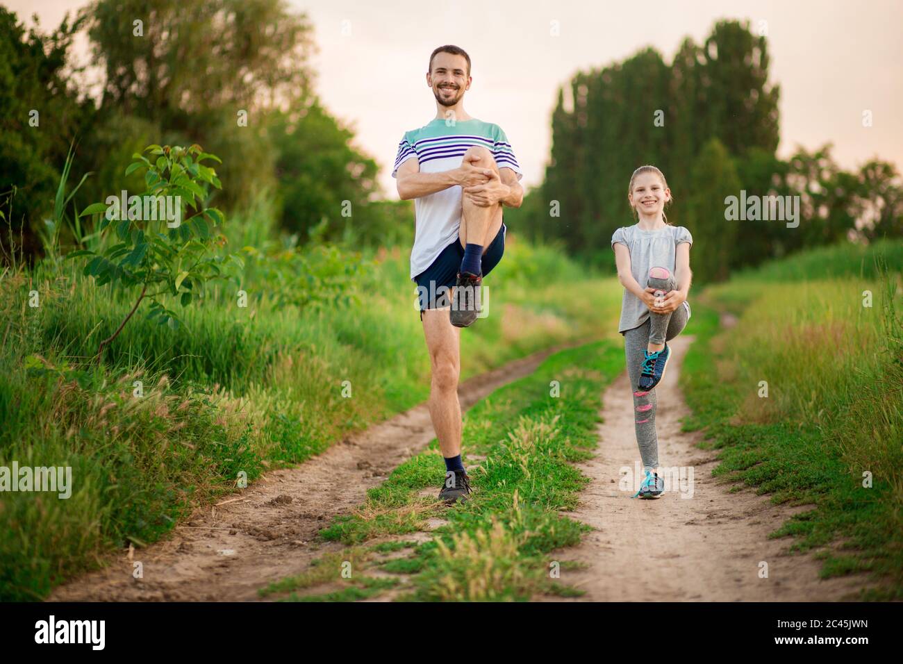 Athletic young father and little daughter do exercises in stadium ...