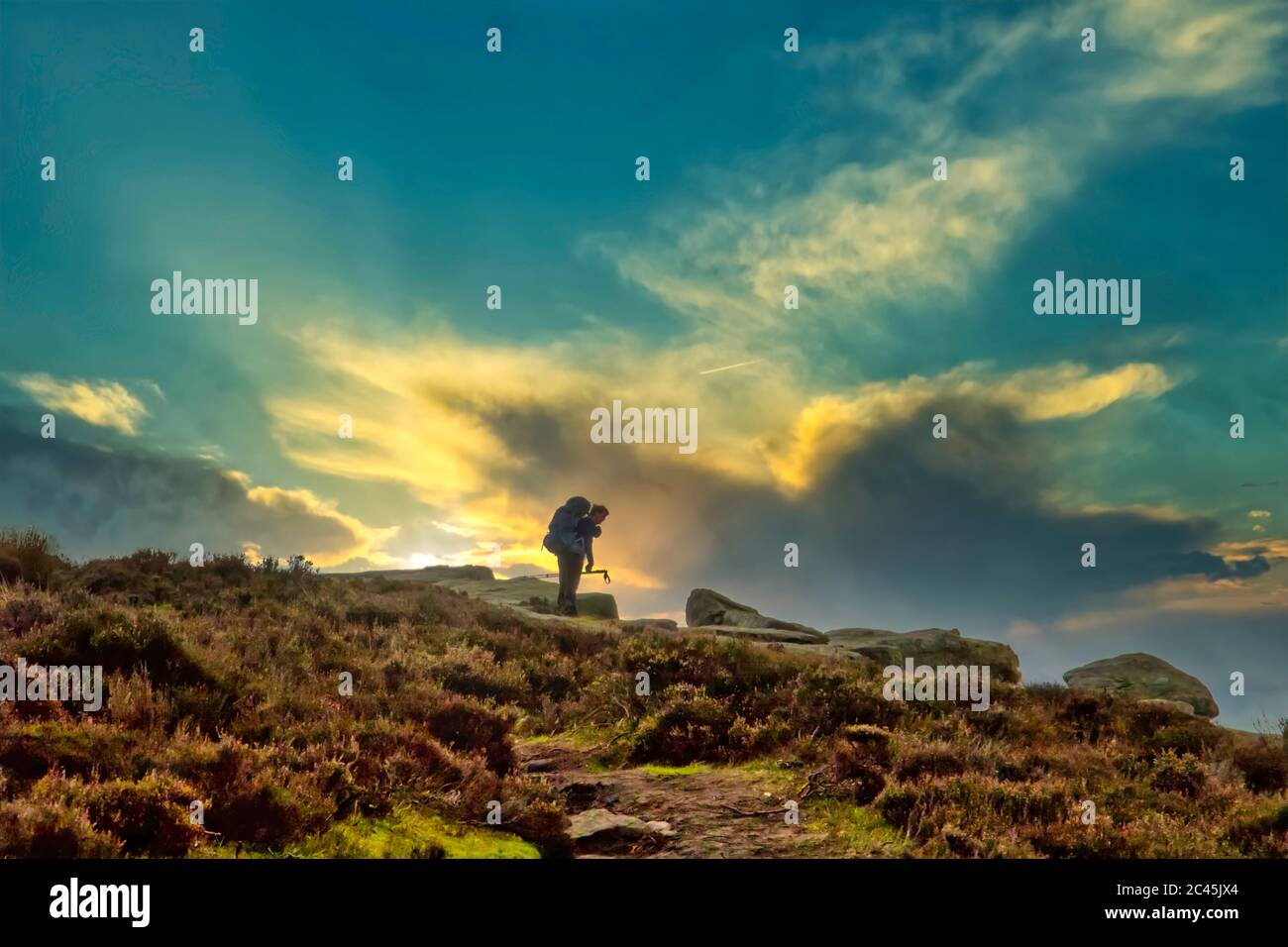 Hiker views a stunning sunset from the ridge at Derwent Edge in the ...