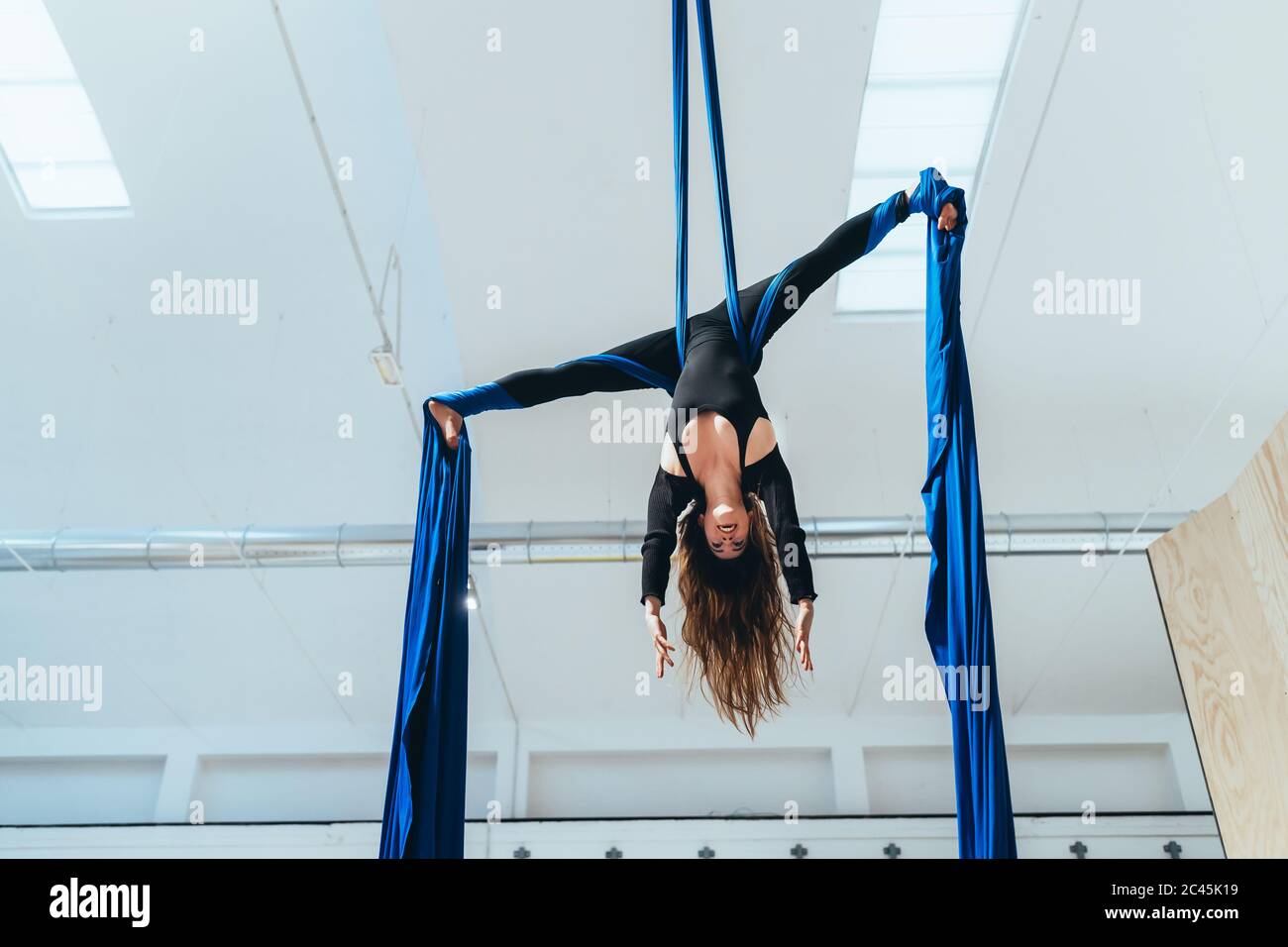 Female acrobat practicing, suspended from blue silk Stock Photo - Alamy