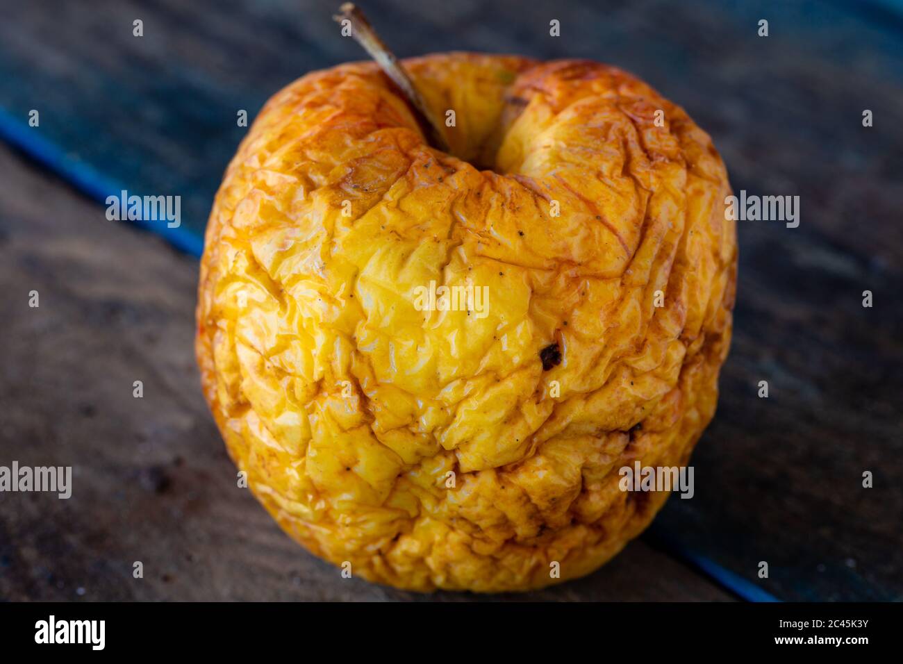 Rotten apple. Spoiled food. Food waste. Apple on old boards Stock Photo ...