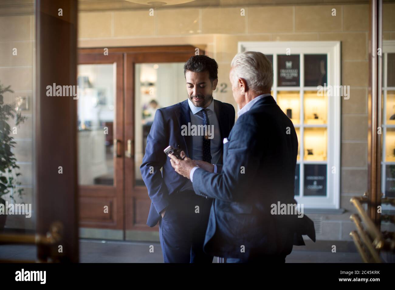Two businessmen standing in hotel lobby, talking Stock Photo - Alamy