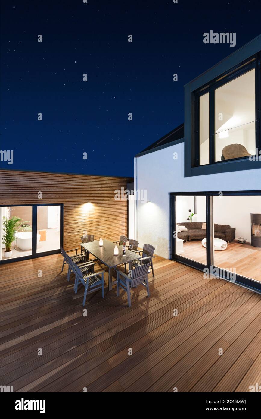 Illuminated house with wooden terrace at night Stock Photo - Alamy