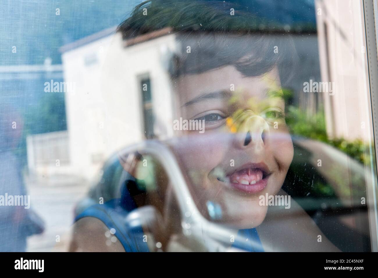A young boy with his nose pressed against a glass window, indoors ...