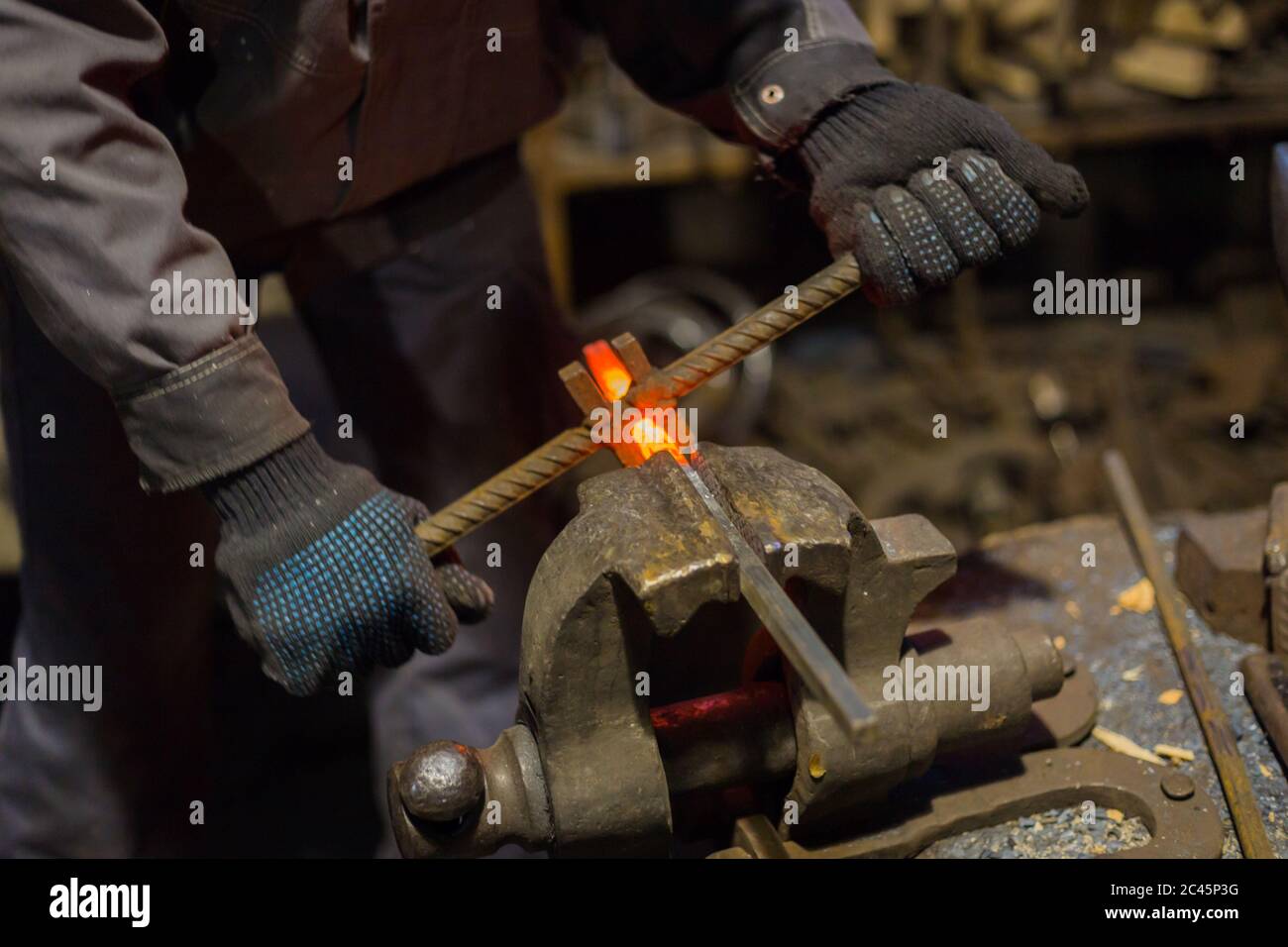 Professional blacksmith working with metal at forge, workshop. Handmade ...