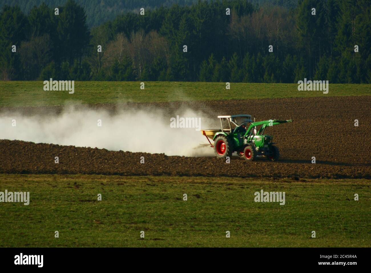 Sowing with tractor and bearing dust cloud Stock Photo - Alamy