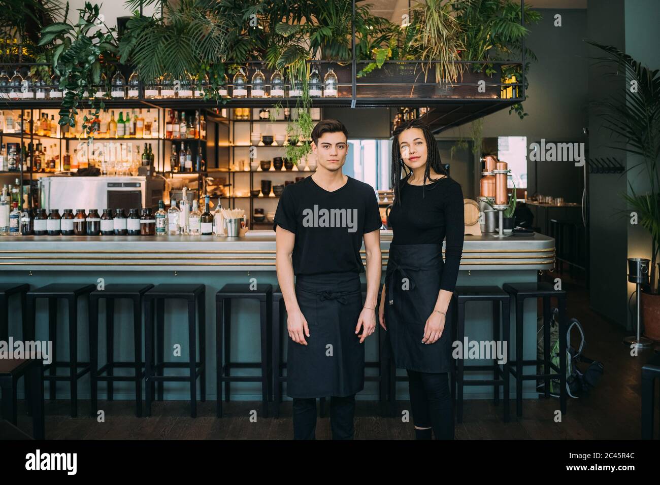 Portrait of young woman and man wearing black clothes standing in front ...