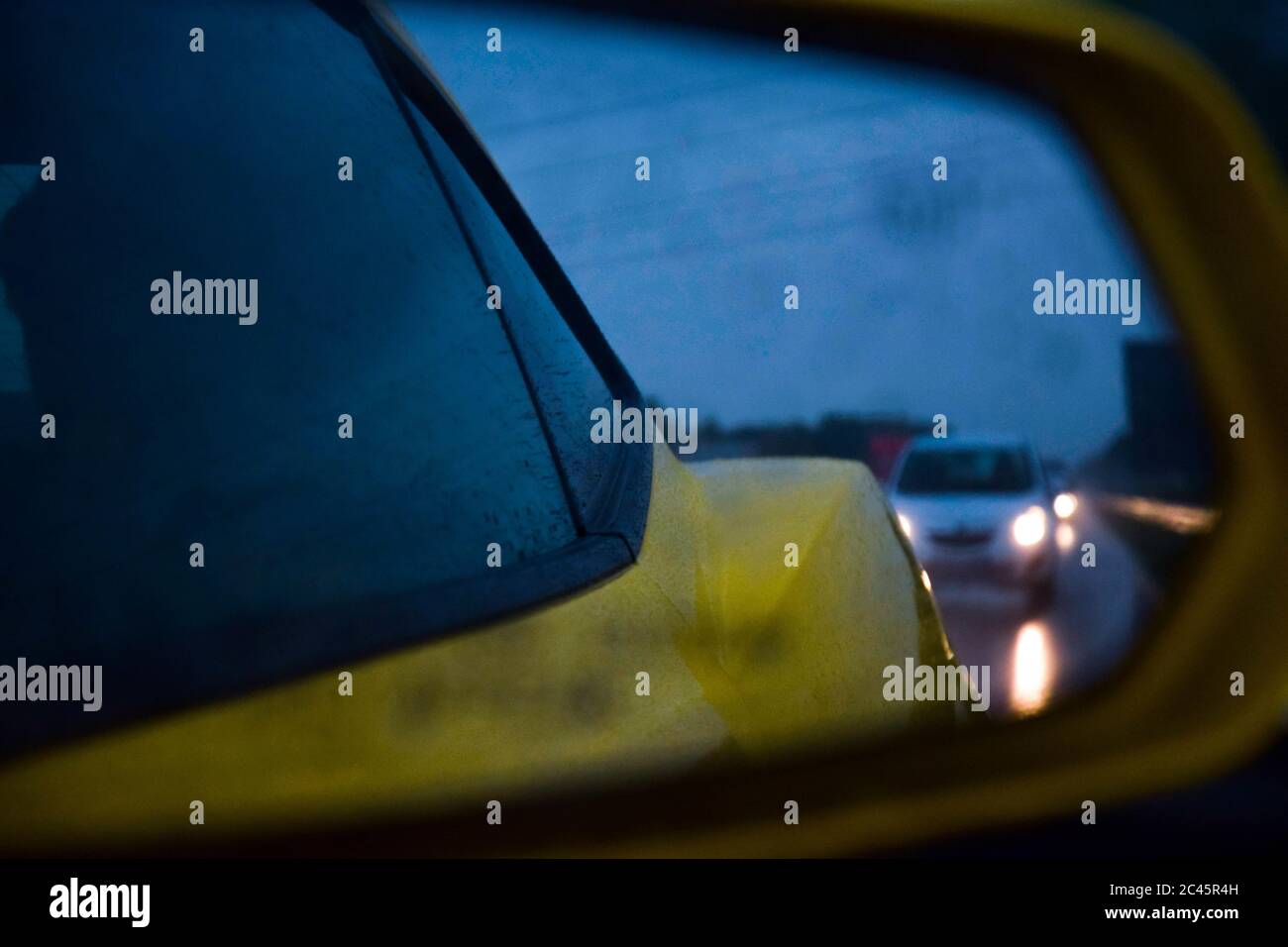 Reflection of cars on the road in the rear view side mirror of a yellow ...