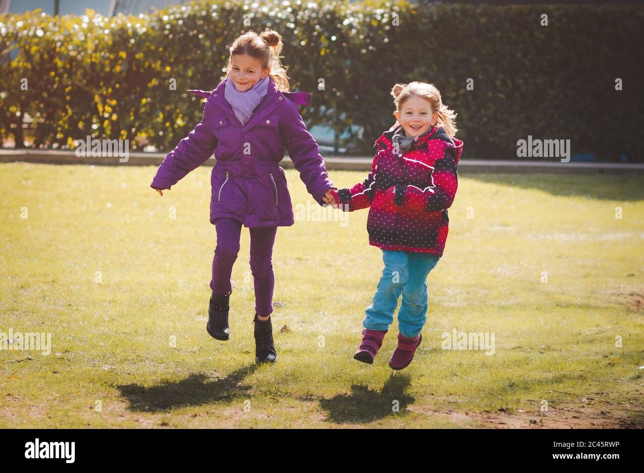 Two happy girls/siblings running holding hands Stock Photo - Alamy