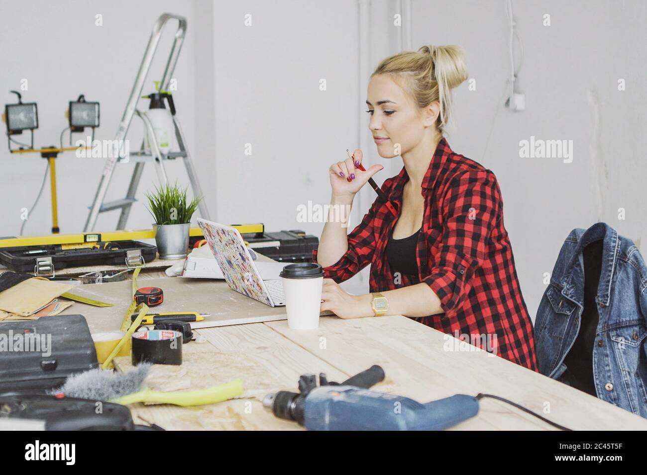 Sitting at workbench female using laptop Stock Photo - Alamy